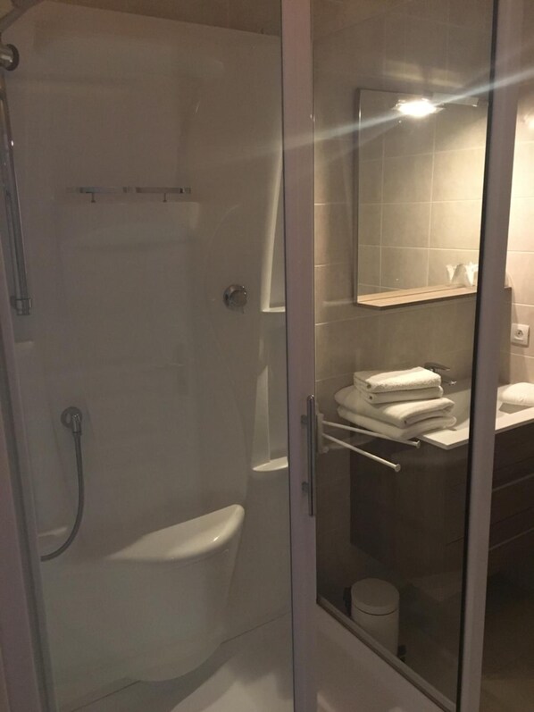 Um banheiro moderno com chuveiro envidraçado, vaso sanitário e pia com porta-toalhas.