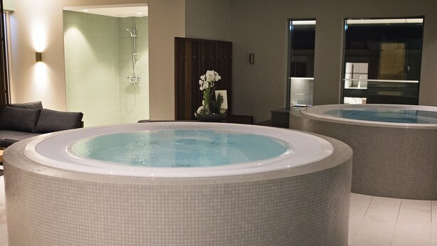 Uma área de spa moderna com duas banheiras de hidromassagem e um chuveiro.