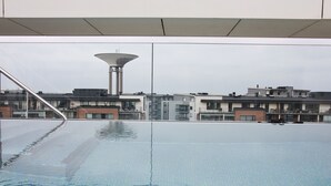 Piscina no terraço com vista para edifícios modernos e um tanque d'água.