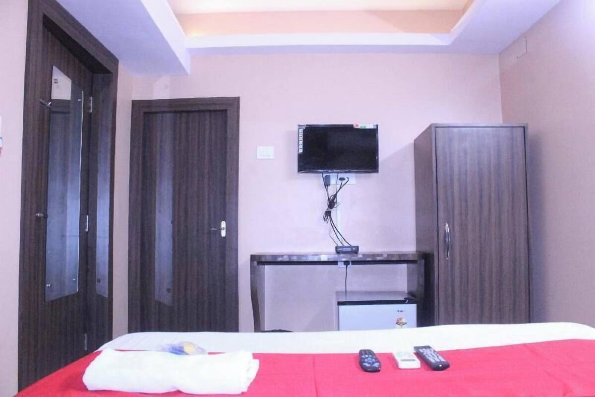 Quarto de hotel com uma cama, escrivaninha, televisão e guarda-roupa.