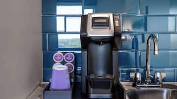 Máquina de café com reservatório de água e suporte para cápsulas em uma bancada de cozinha.