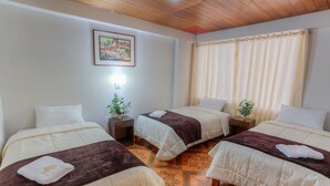Quarto de hotel com três camas, teto de madeira, um quadro na parede e janela com cortinas.