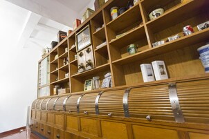 Um armário de madeira em estilo antigo, com várias gavetas e prateleiras, contendo diversos itens como potes, livros e objetos decorativos.