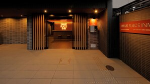 Entrada de um hotel com balcão de recepção e placa com a inscrição 'SMART PLACE INN'.