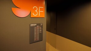 Uma parede com uma grande placa laranja com a inscrição '3F' e uma placa de rota de emergência menor abaixo.