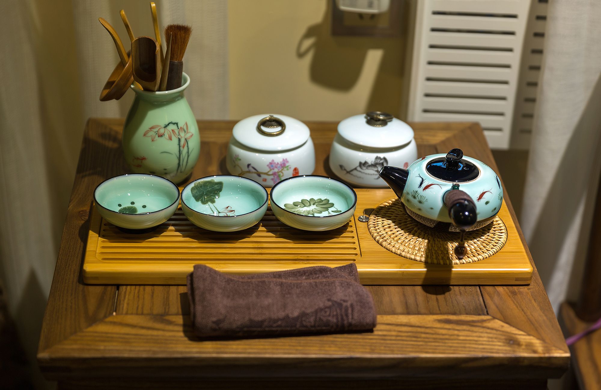 Uma mesa de madeira com três tigelas, um bule e um vaso com pincéis.