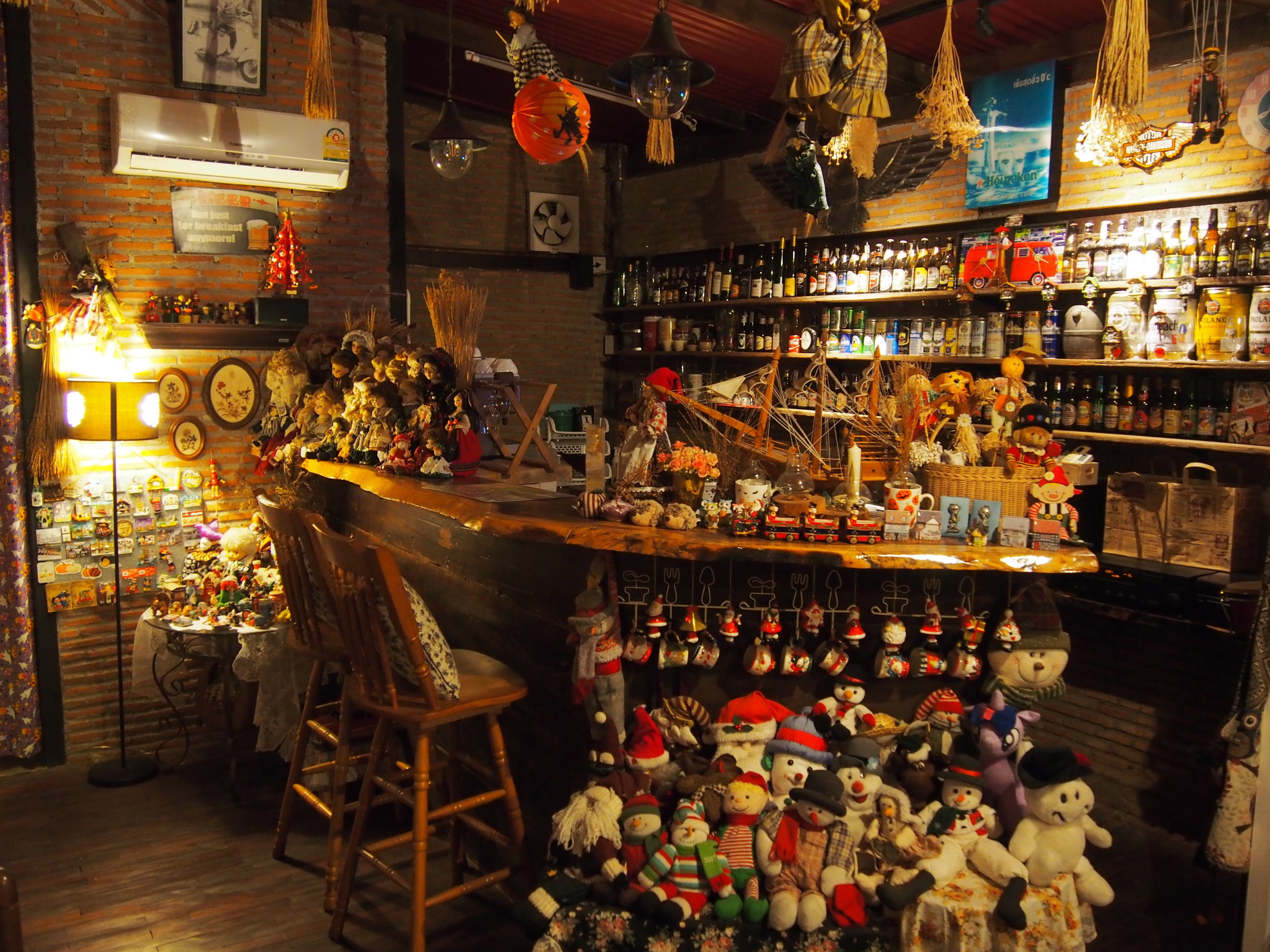 Um bar com balcão de madeira, estantes de garrafas e diversas decorações, incluindo animais de pelúcia e um modelo de navio.