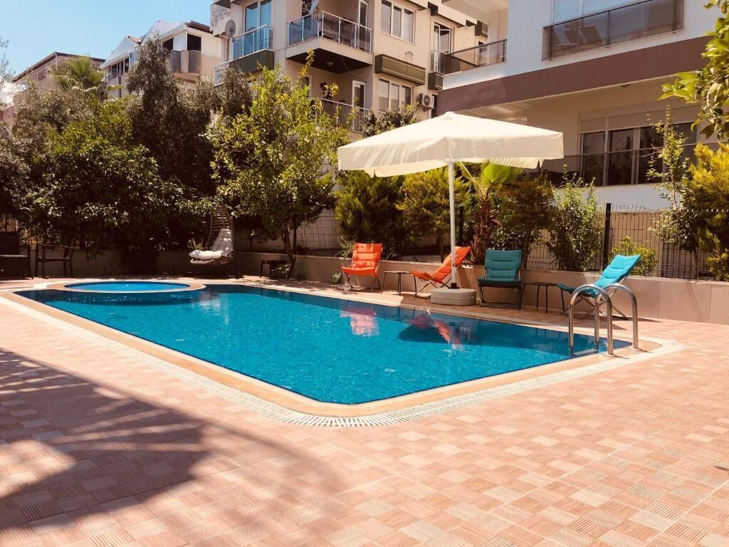 Piscina com espreguiçadeiras e um guarda-sol.