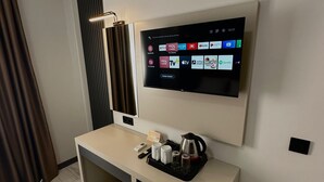 Quarto de hotel moderno com televisão de tela plana na parede exibindo diversos serviços de streaming.