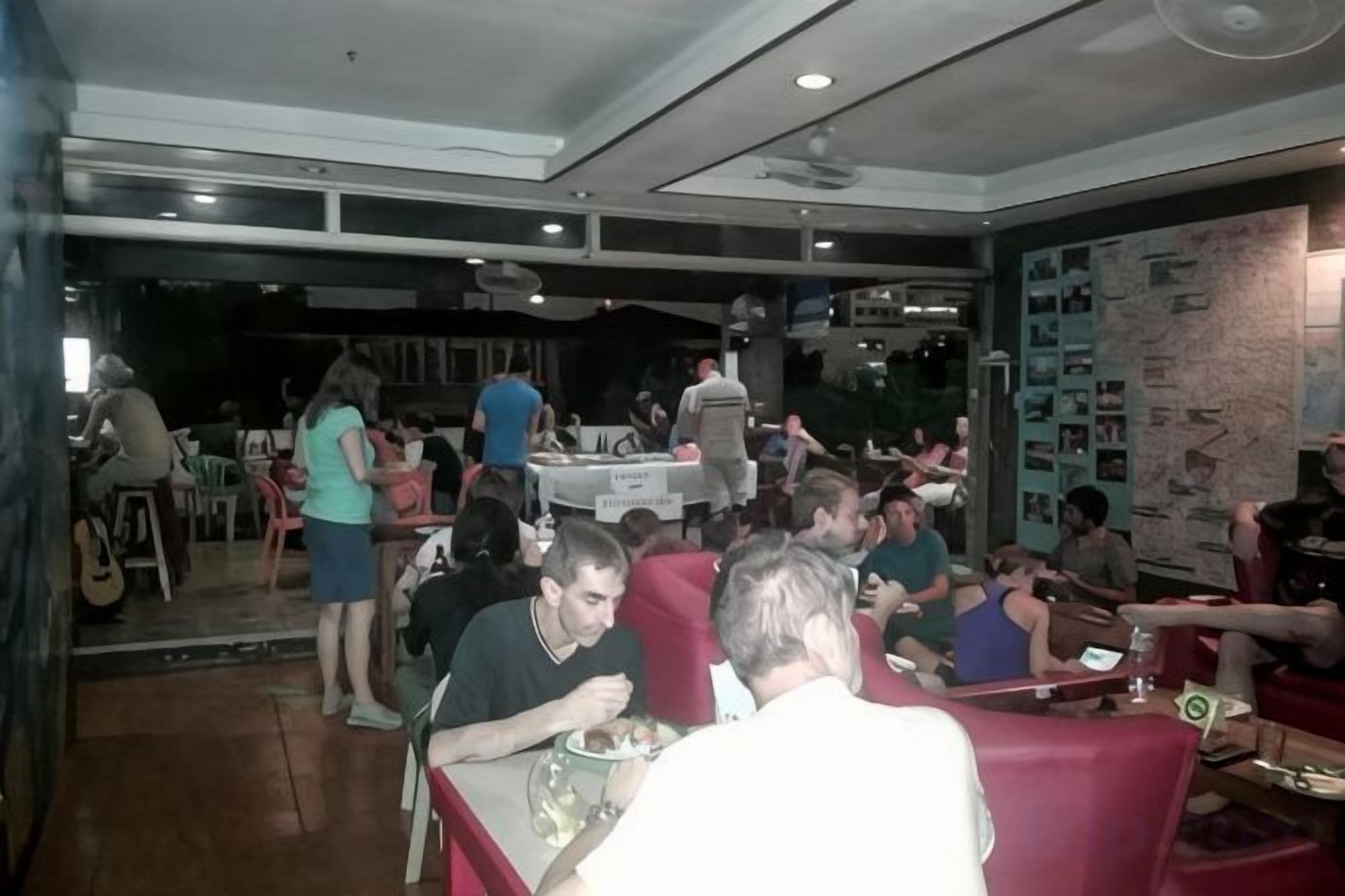Interior de restaurante com mesas, cadeiras, balcão e ventoinha no teto.