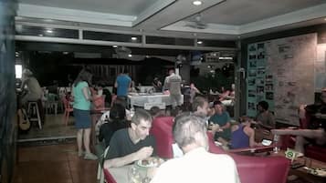 Interior de restaurante com mesas, cadeiras, balcão e ventoinha no teto.
