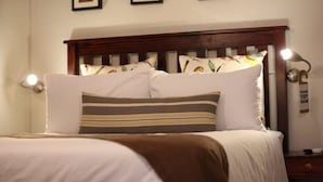 Cama bem arrumada com travesseiro listrado, cabeceira de madeira e abajur.