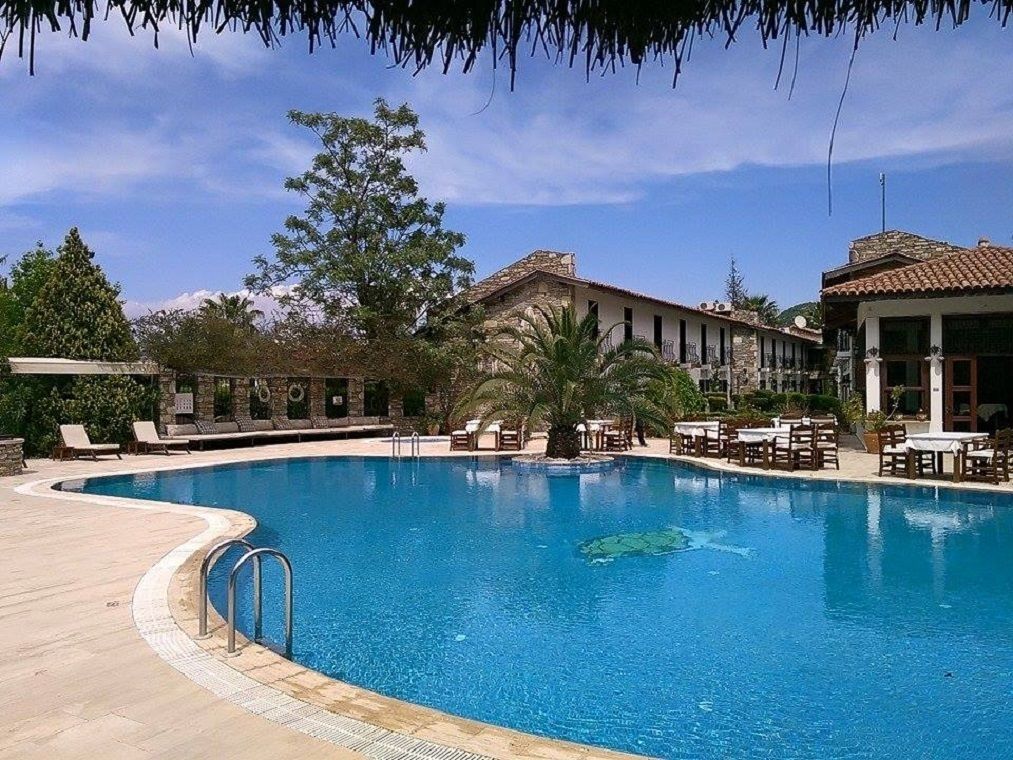 Piscina com espreguiçadeiras e um edifício ao fundo.