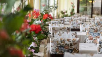 Mesa após mesa com toalhas floridas e cadeiras, indicando um ambiente de jantar formal.