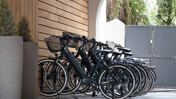 Uma fileira de bicicletas estacionadas sob uma estrutura de madeira, com vista para o verde lá fora.