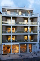 Um hotel CONCIA com vários andares, com varandas, área de estar ao ar livre e entrada no andar térreo visível.