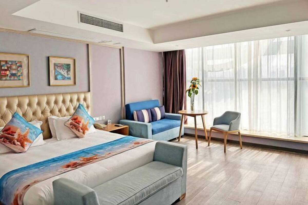 Quarto de hotel com uma cama grande, um sofá, uma mesa pequena e uma cadeira.