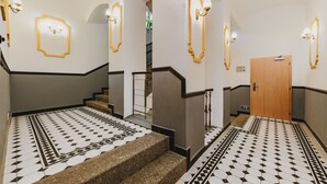Uma escadaria com piso estampado e arandelas na parede.