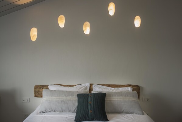 Cama com cabeceira de madeira, duas almofadas e um cobertor de tricô.