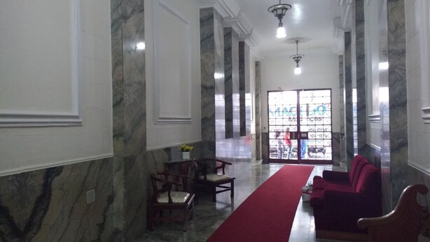 Um hall com paredes de mármore, tapete vermelho e mobiliário de madeira.