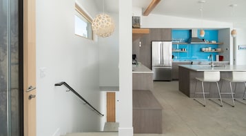 Cozinha moderna com ilha central, eletrodomésticos de aço inoxidável e banquetas.