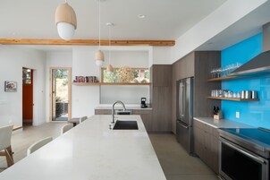 Cozinha moderna com ilha central, eletrodomésticos embutidos e parede azul decorativa.