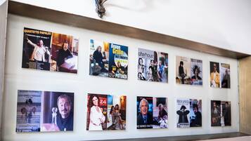 Paredes decoradas com cartazes emoldurados de diversos eventos e pessoas.