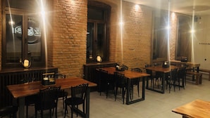 Um restaurante com paredes de tijolo, mesas de madeira e cadeiras pretas.