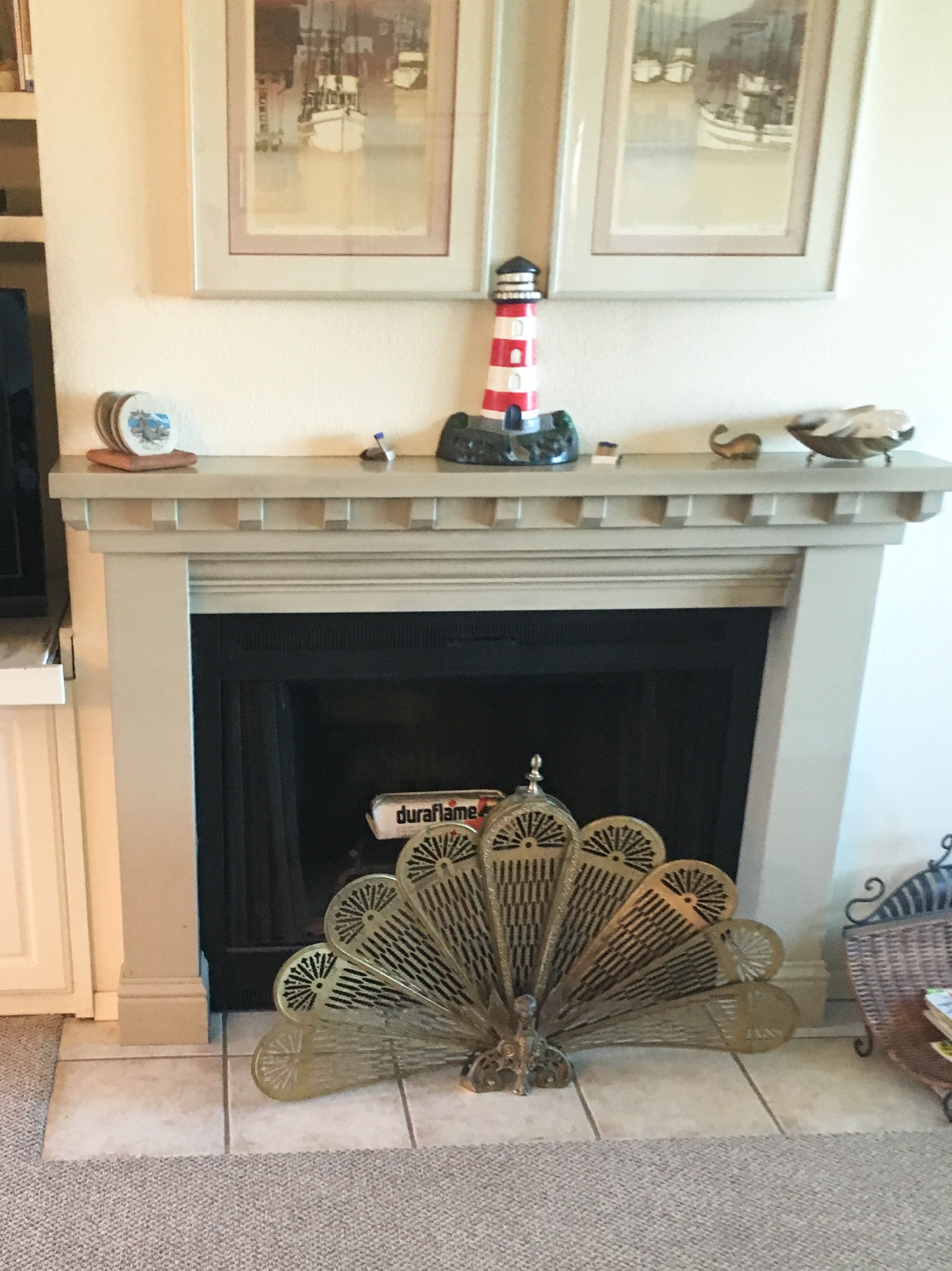 Uma lareira com manto decorativo, uma pena de pavão ornamental e uma pequena estatueta de pássaro.