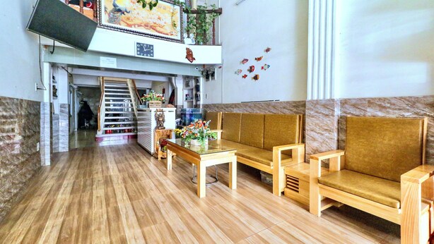 Um hall com piso de madeira, um sofá, uma mesa e uma televisão na parede.