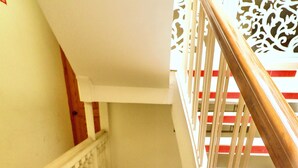 Uma escadaria com balaústres elaborados e um corrimão listrado em vermelho e branco.
