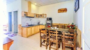 Uma cozinha com armários de madeira, uma mesa de jantar com cadeiras, uma geladeira e um micro-ondas.