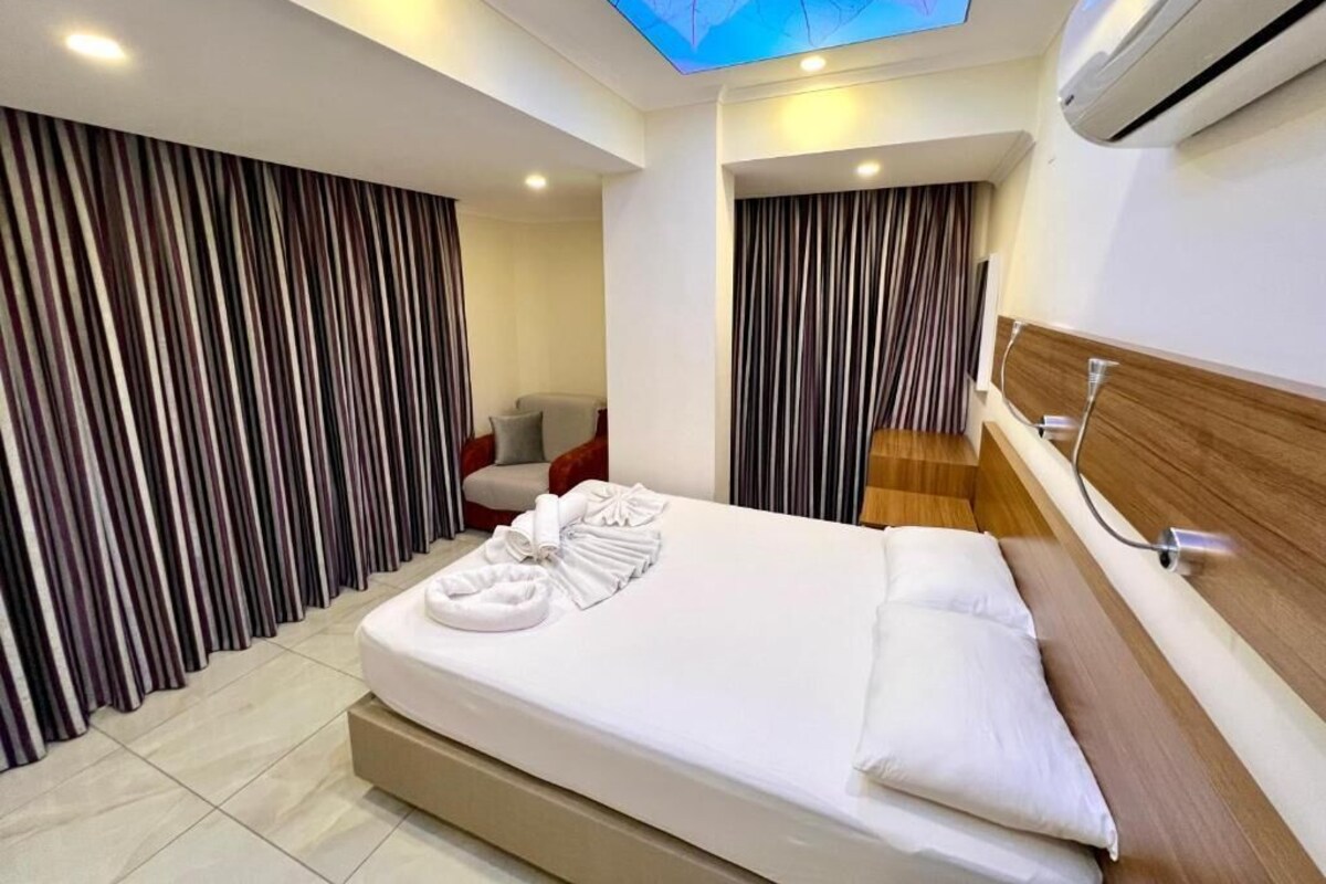Quarto de hotel moderno com cama, escrivaninha e luminária no teto.