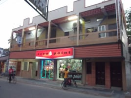 Um edifício com placa indicando 'ponto zero', com fachada de vidro e uma bicicleta estacionada em frente.