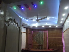 Quarto com ventoinha no teto, iluminação embutida e escada de madeira.