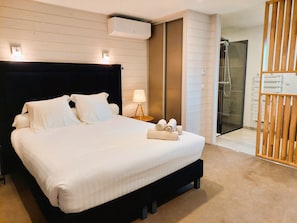Quarto de hotel com uma cama grande, uma luminária de cabeceira e uma área de chuveiro.
