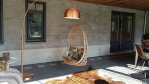 Quarto com cadeira suspensa, mesa e cadeira, e teto de madeira.
