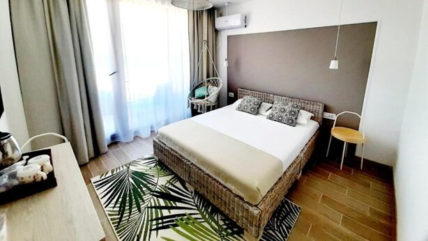 Quarto de hotel moderno com uma cama grande, uma mesa de jantar e uma cadeira.