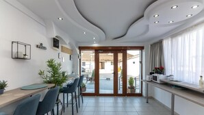 Cozinha moderna com área de refeições, destacando uma ilha central, banquetas de bar e uma grande janela com cortinas.
