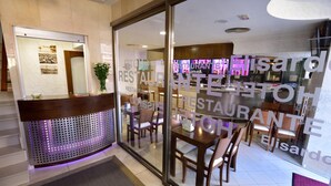 Interior de restaurante com balcão de recepção, área de estar e bar.