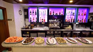 Uma área de bar com um balcão de frutos do mar, prateleiras cheias de garrafas de bebidas e uma máquina de café.