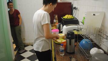 Uma cozinha com piso xadrez, uma cafeteira, uma garrafa de água e uma fruteira.