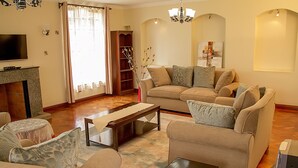 Uma sala de estar com sofá, mesa de centro, televisão e lareira.