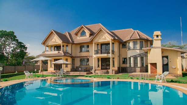 Uma casa grande com piscina, várias varandas e mobiliário de exterior.