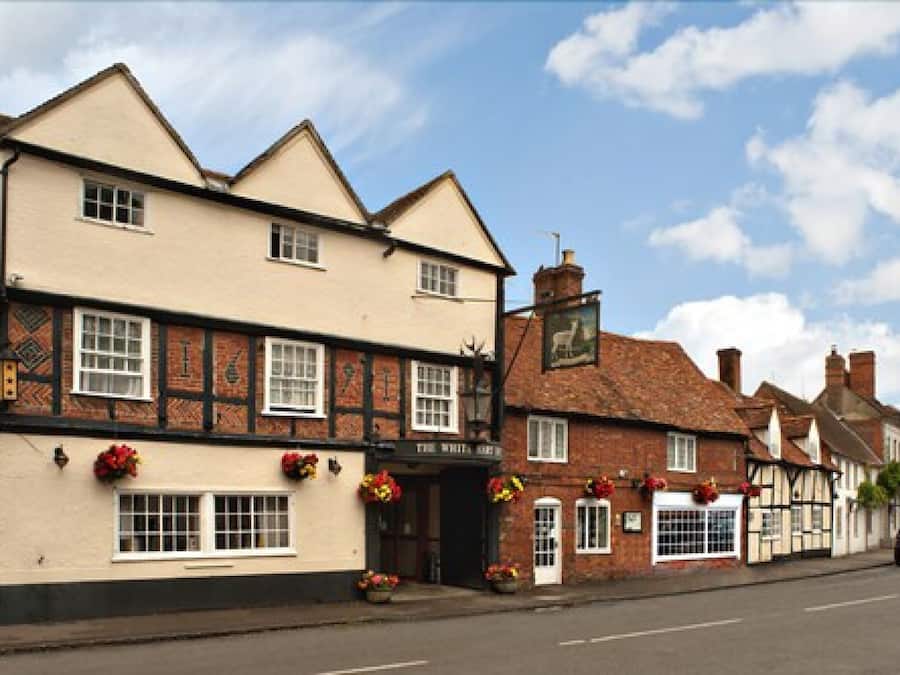 Um pub tradicional com fachada branca e estrutura de madeira, exibindo uma placa com a inscrição "The White Lion".