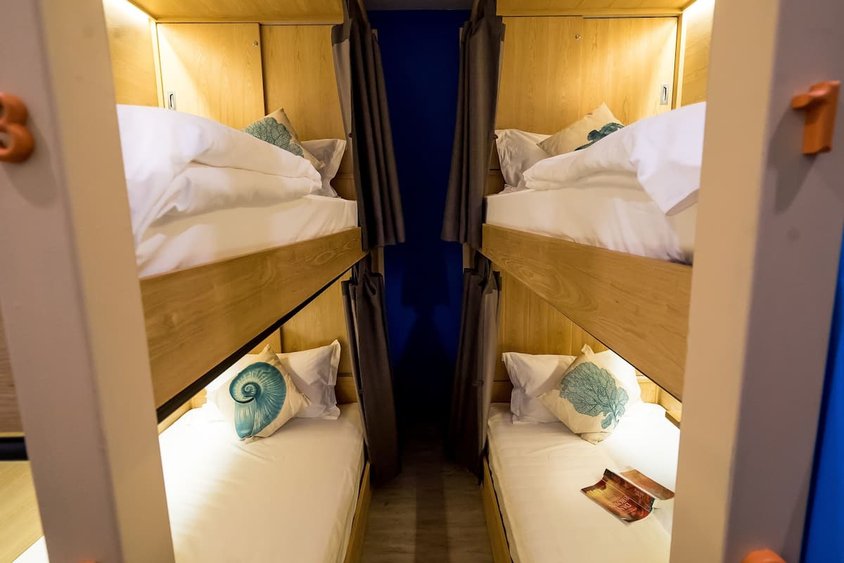 Quarto com beliche de madeira, com duas camas, cada uma com roupa de cama branca e almofadas decorativas.