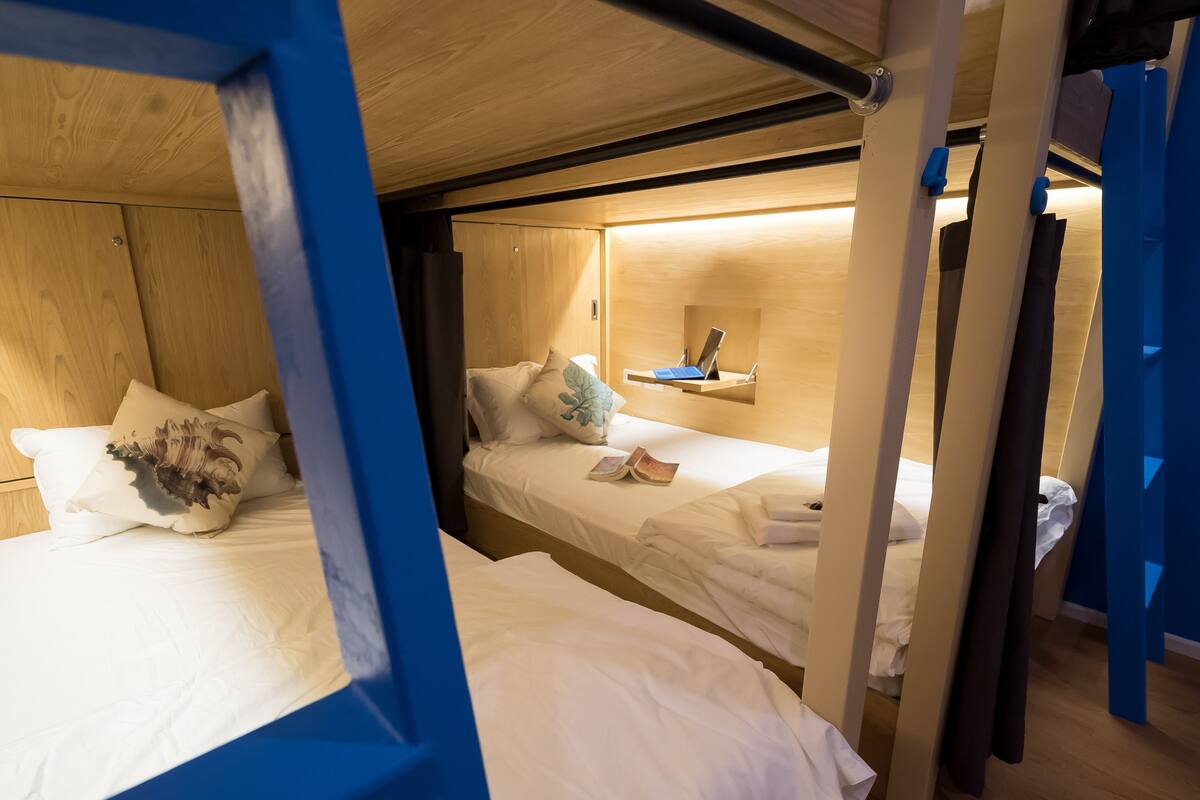 Quarto com beliches, paredes de madeira e prateleira sobre a cama inferior.