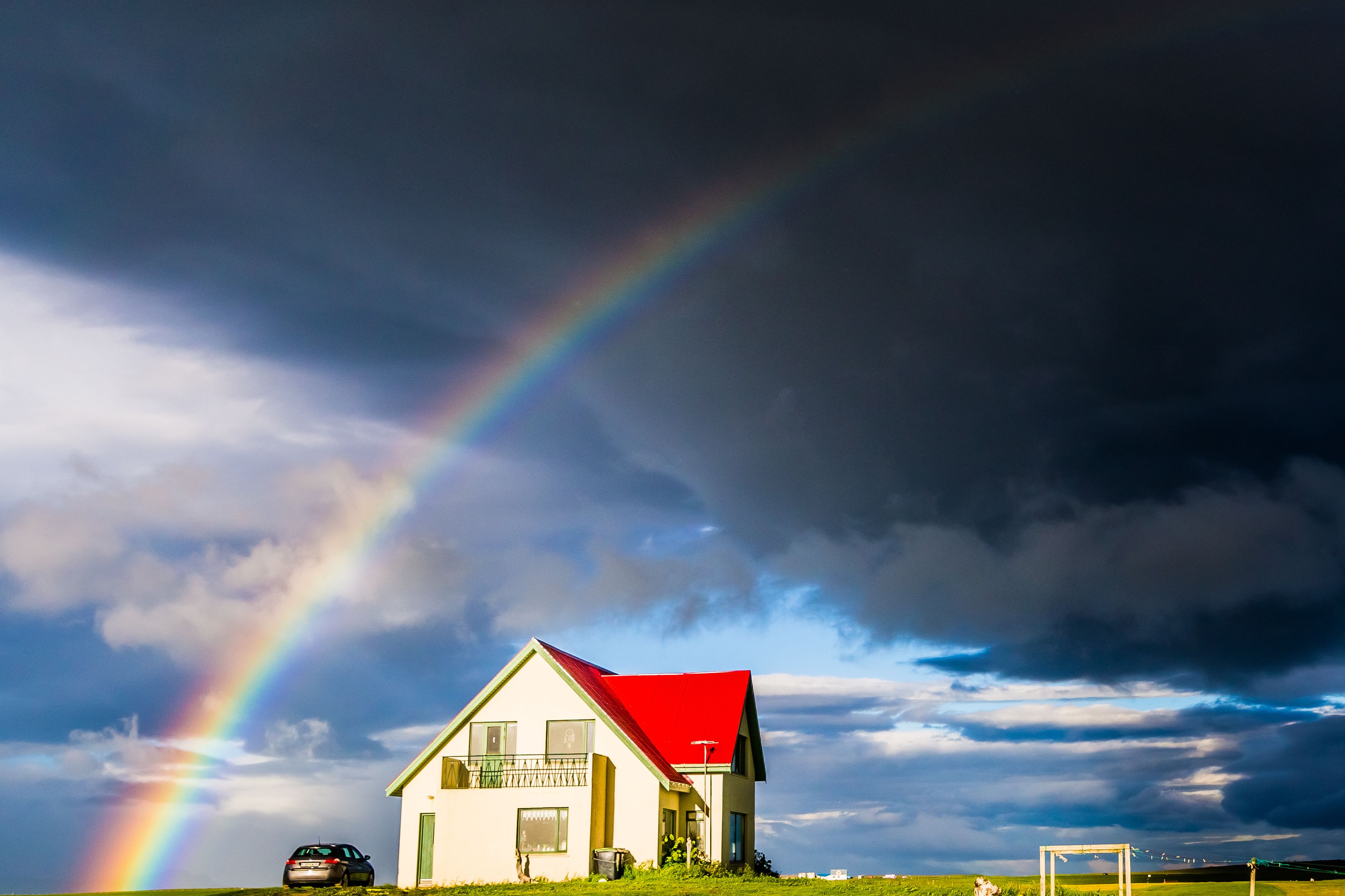 Uma casa com telhado vermelho e um arco-íris visível no céu.