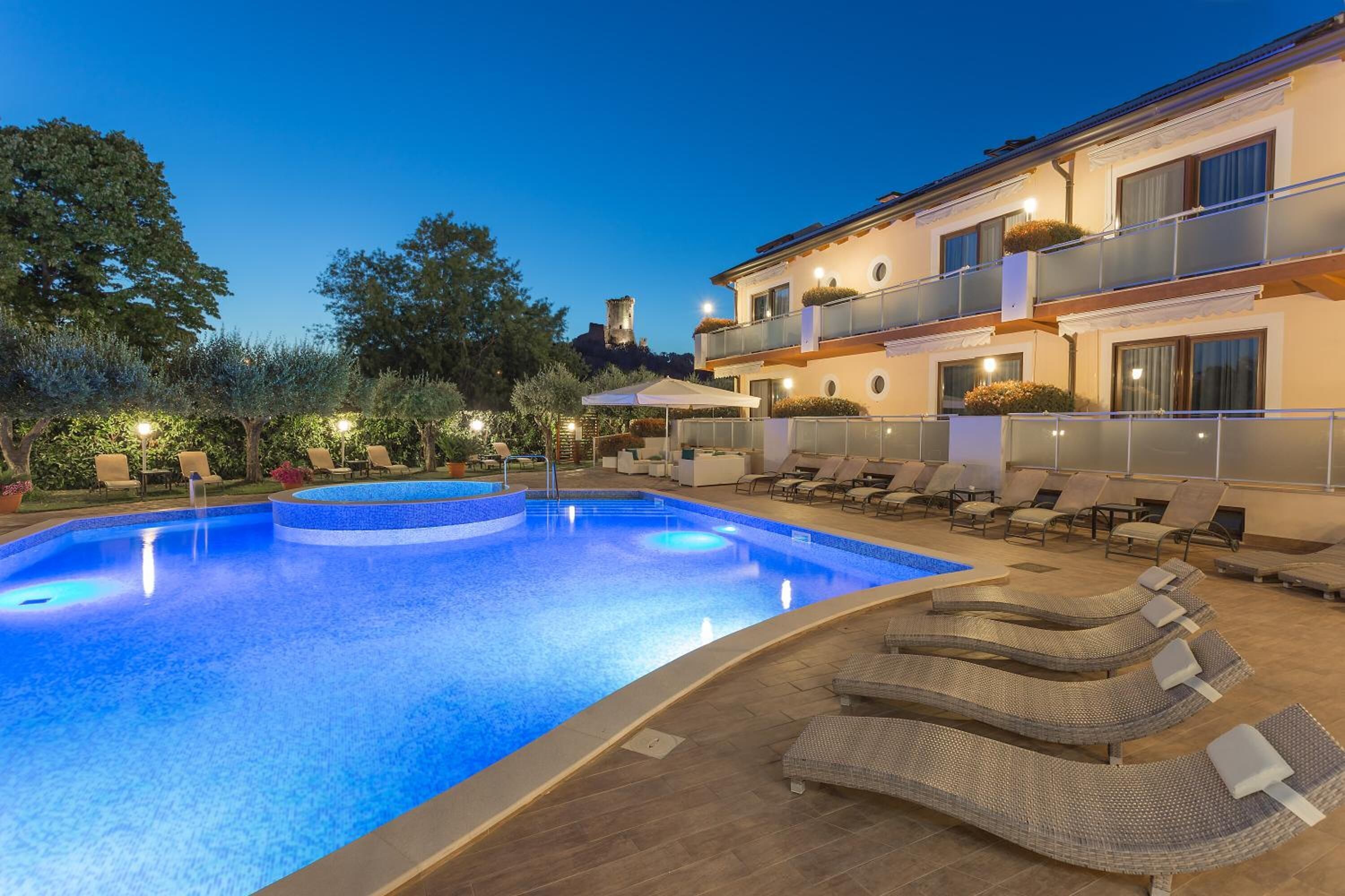 Piscina com espreguiçadeiras e um edifício com varandas.