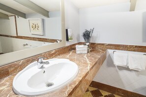 Casa de banho com lavatório branco, espelho grande e bancada de mármore.